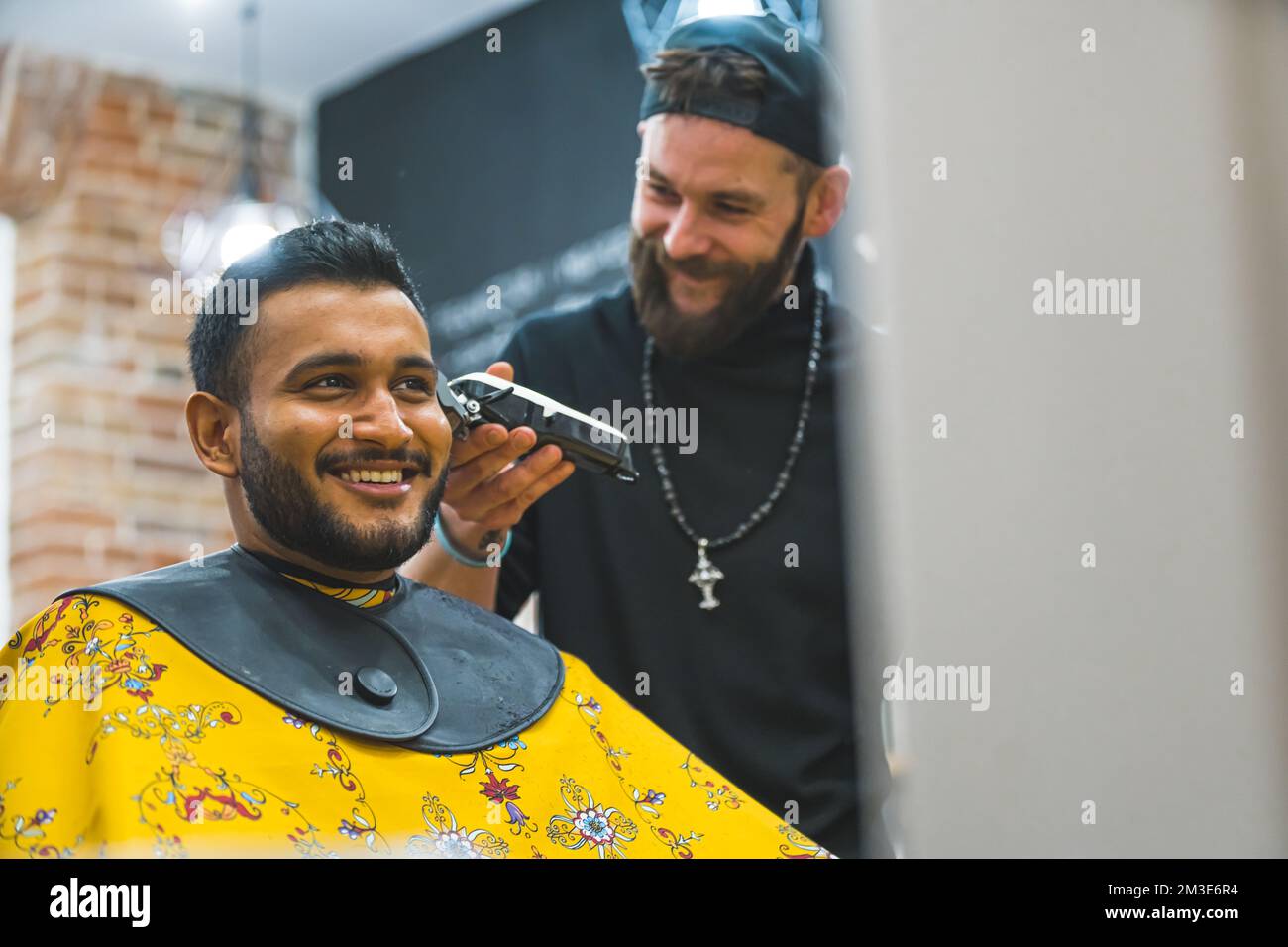 young bearded man getting haircut by a barber while sitting in a chair ...