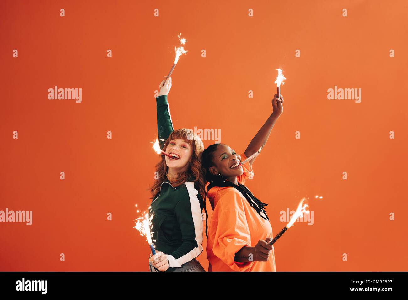 Female friends smiling at the camera while lifting bengal lights in ...