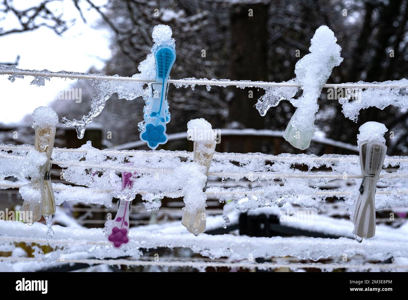 Frozen iced clothes pegs covered in snow on a washing line during a ...