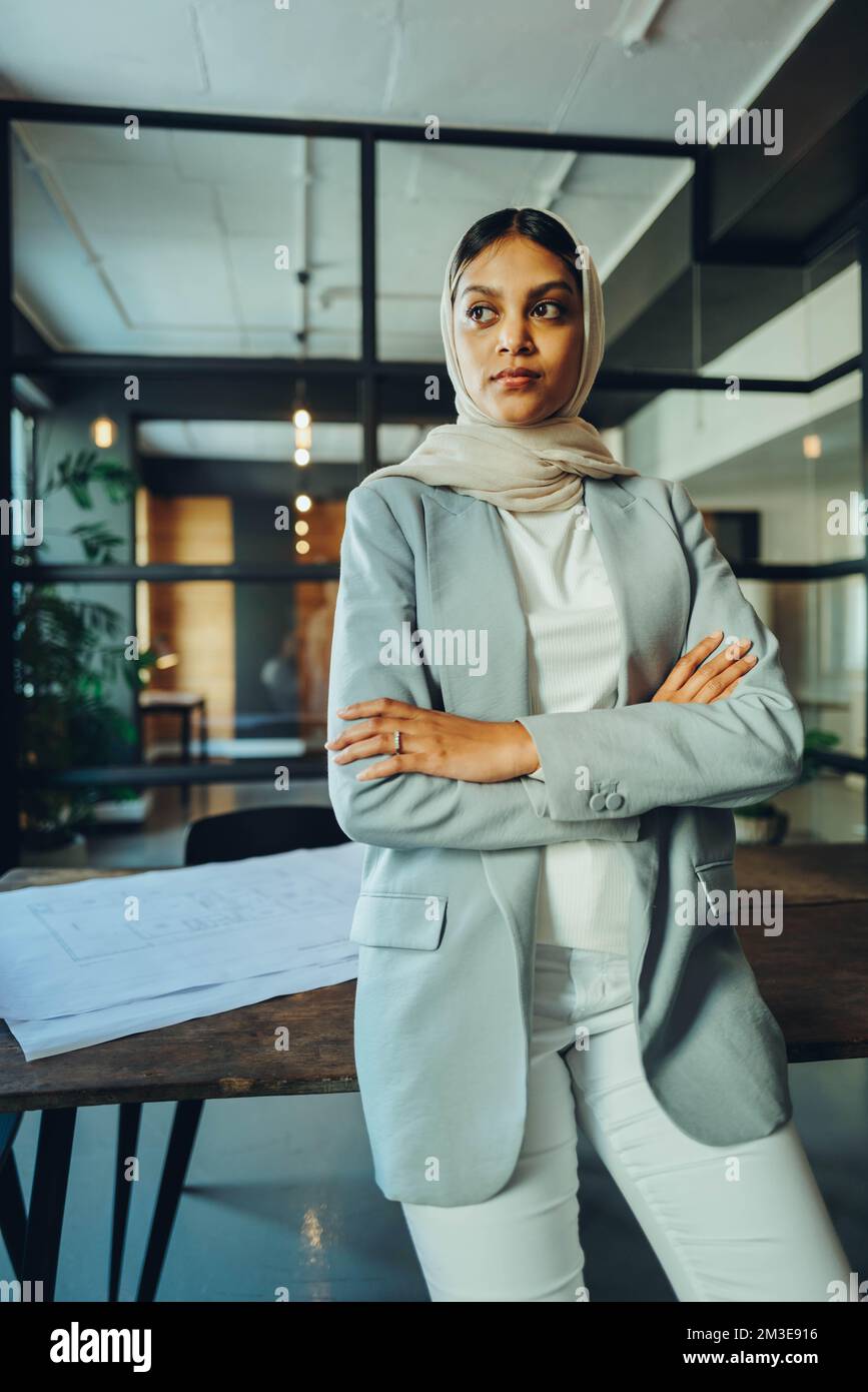 Ethnic Muslim businesswoman looking away thoughtfully while standing in ...