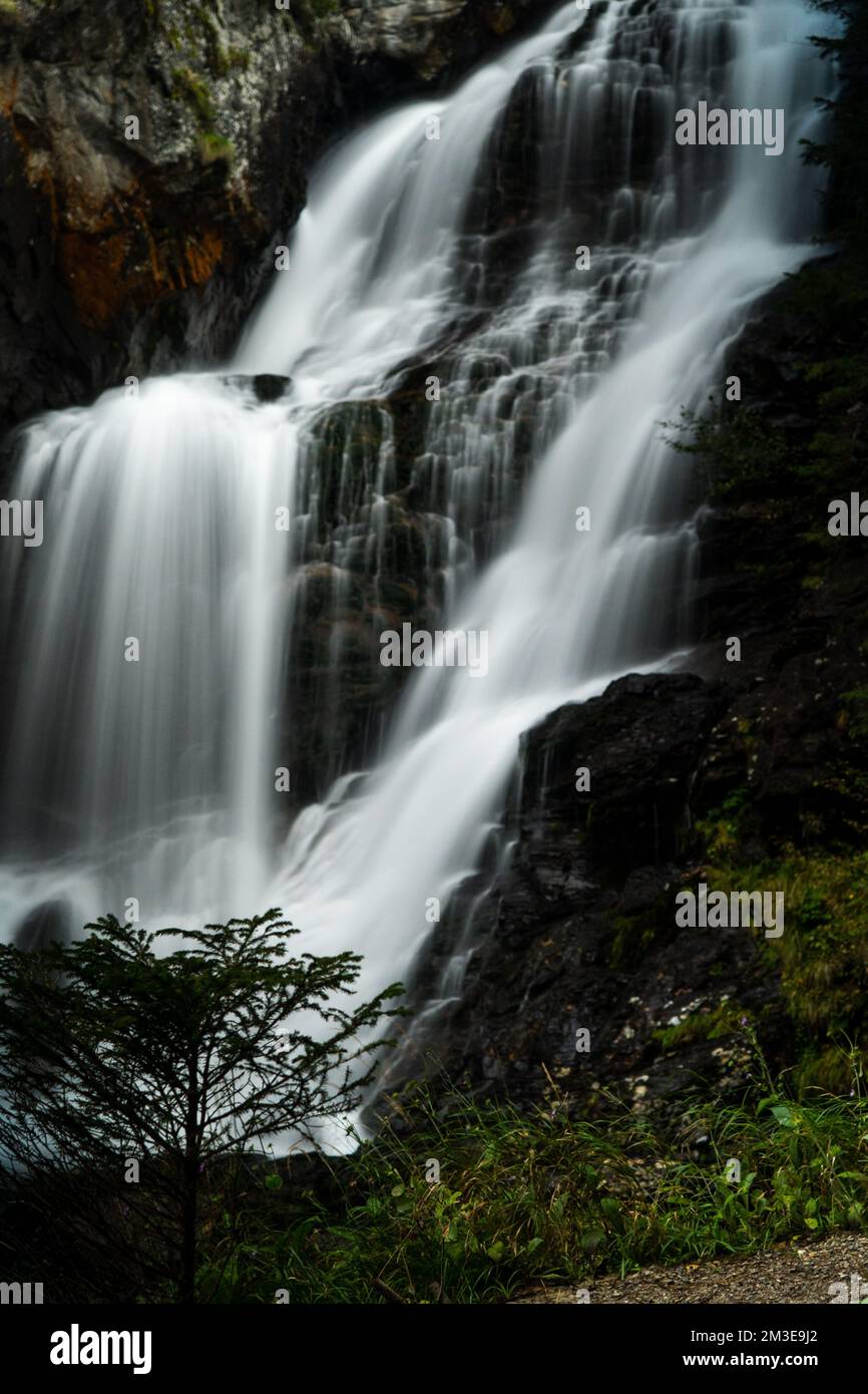 A vertical long exposure of a waterfall flowing down into a lake ...