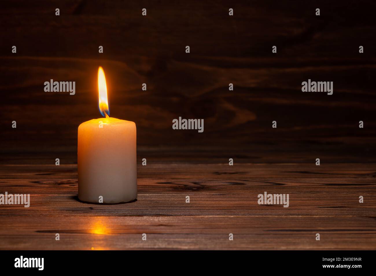 one burning candle on wooden background in minimalist room interior ...