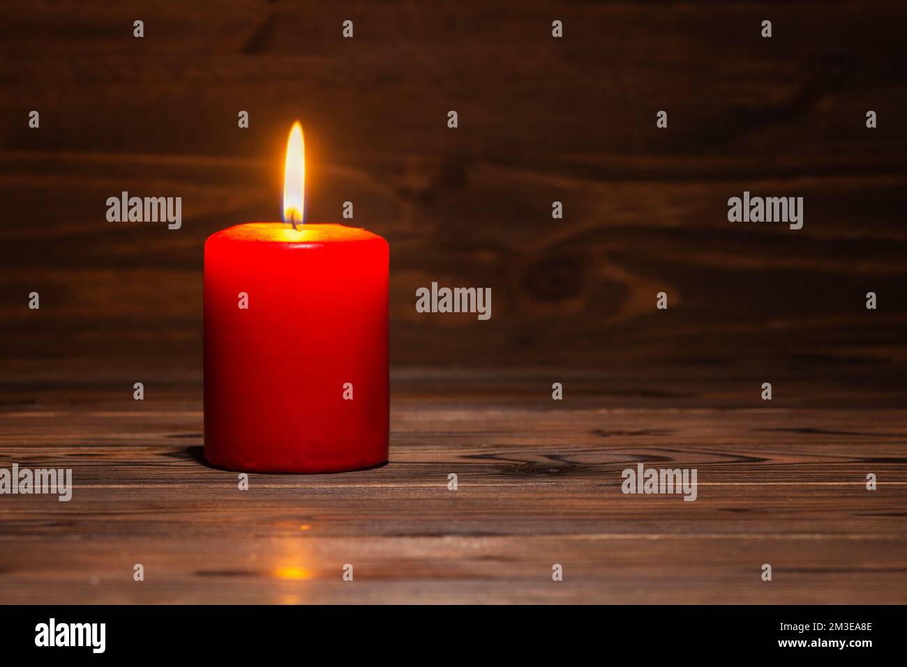 red burning candle on wooden background in minimalist room interior ...