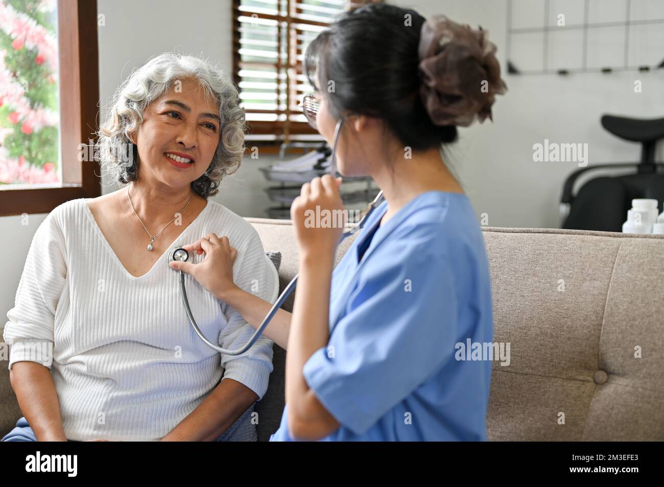 Happy 60s retire Asian woman talking and checking health, visiting her personal doctor at the ...