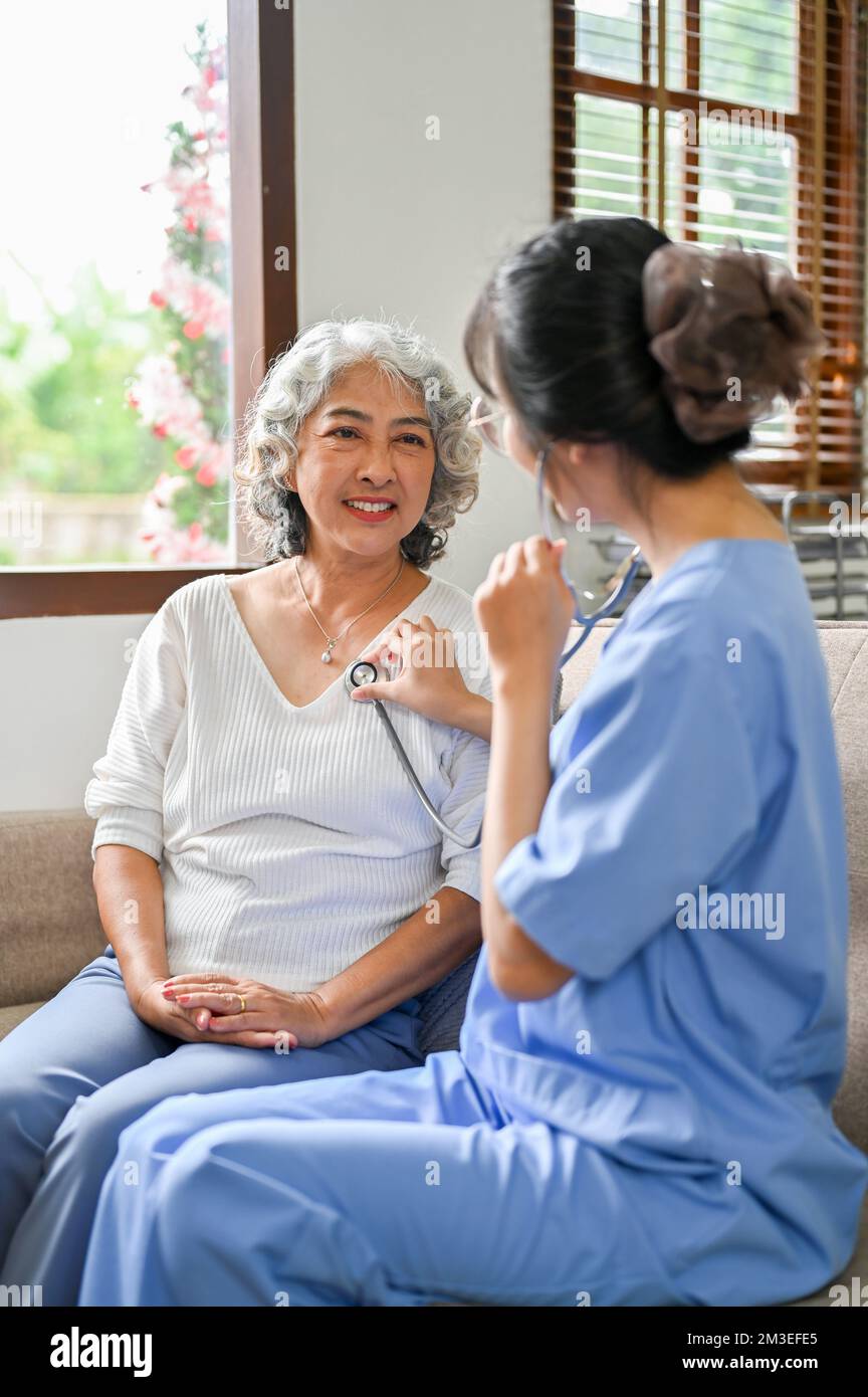 Young Asian female doctor using a stethoscope to listen to a patient's ...