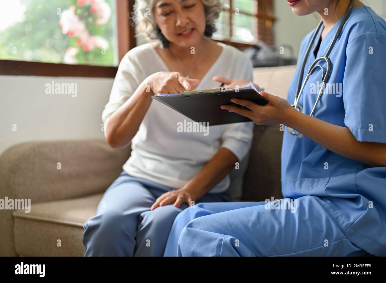 An elderly Asian woman is talking, visiting her doctor at the clinic ...