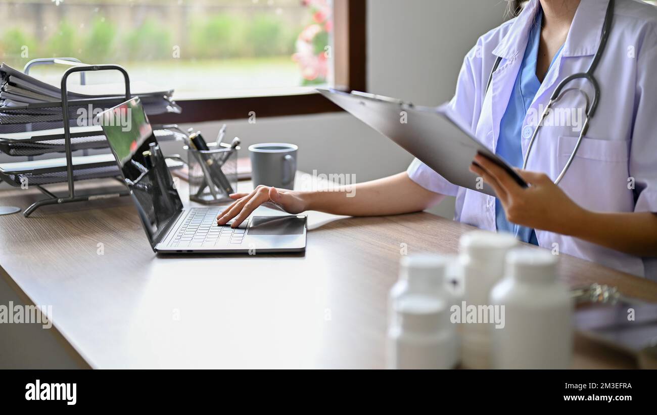 Professional and smart millennial Asian female doctor in uniform using ...