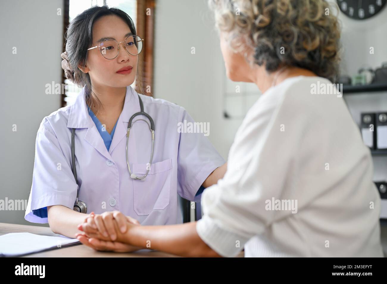 Professional and focused young Asian female doctor talking and ...