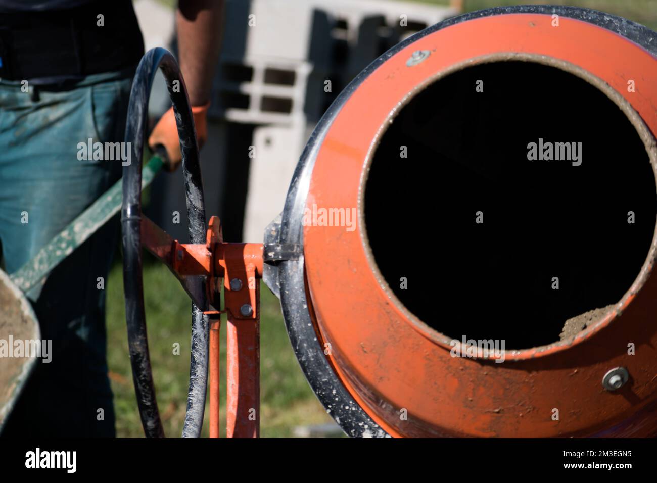 Bricklayer preparing concrete with a cement mixer to build a wall at a ...