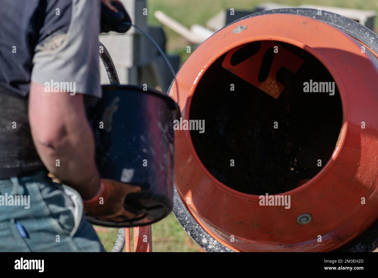Bricklayer preparing concrete with a cement mixer to build a wall at a ...