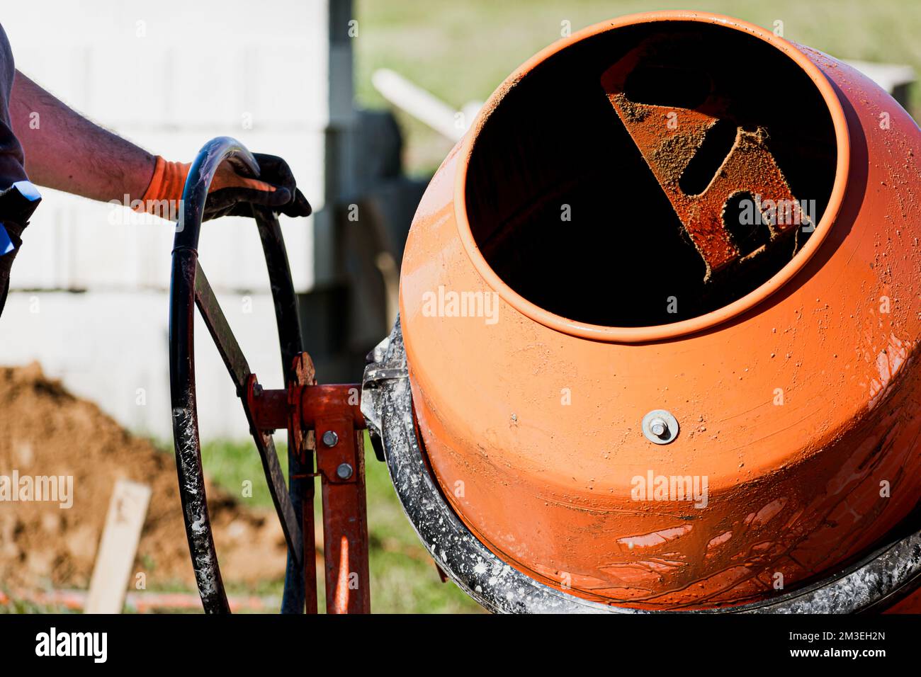 Bricklayer preparing concrete with a cement mixer to build a wall at a ...