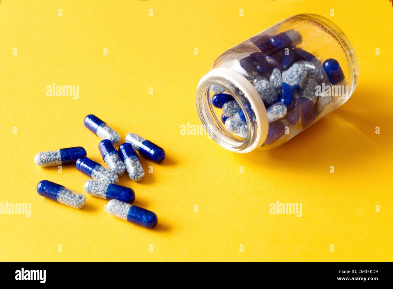blue vitamin capsules spilled out of jar on yellow background Stock ...