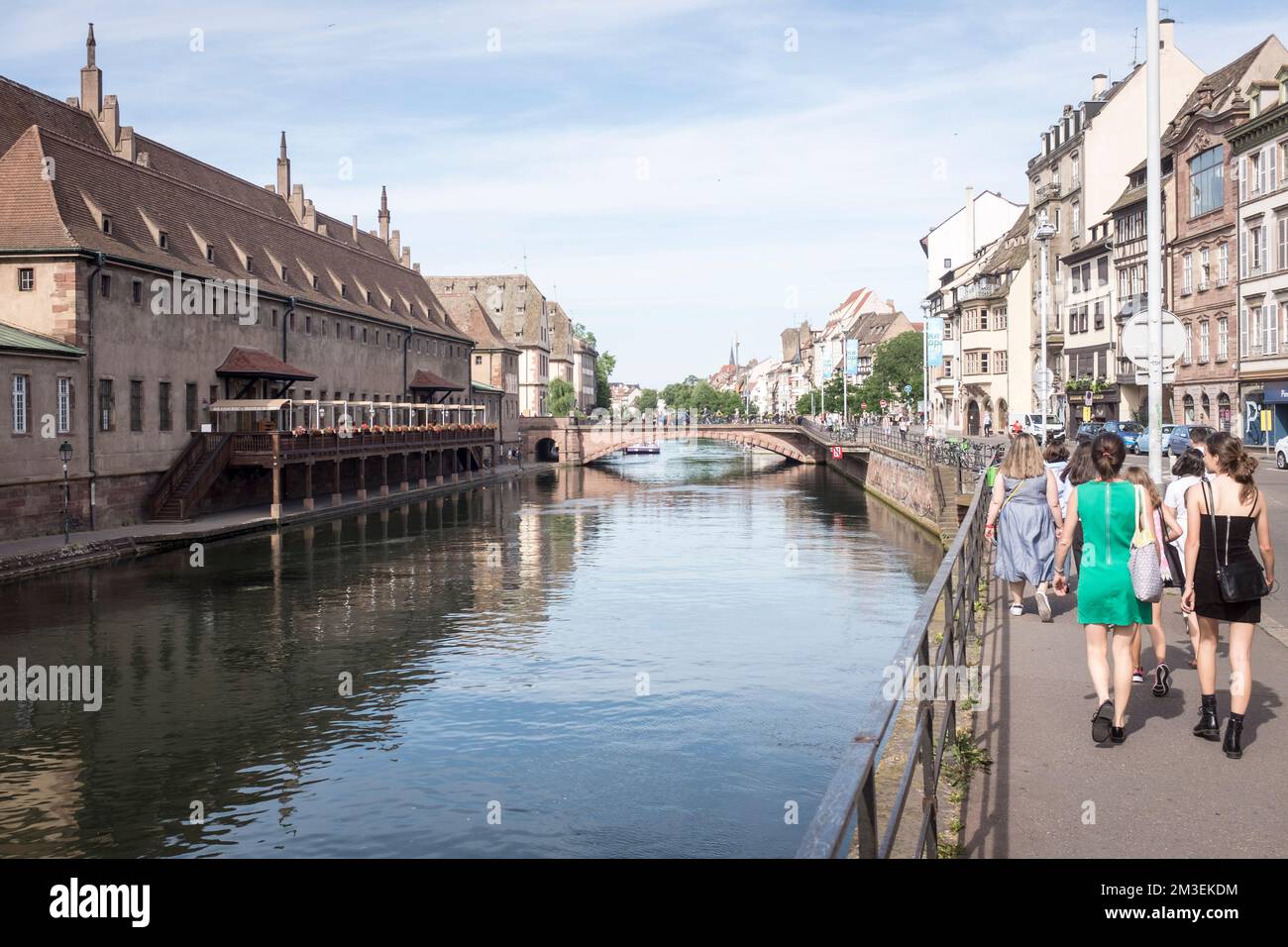 People walk by the former customs house on the Ill river on a sunny day ...