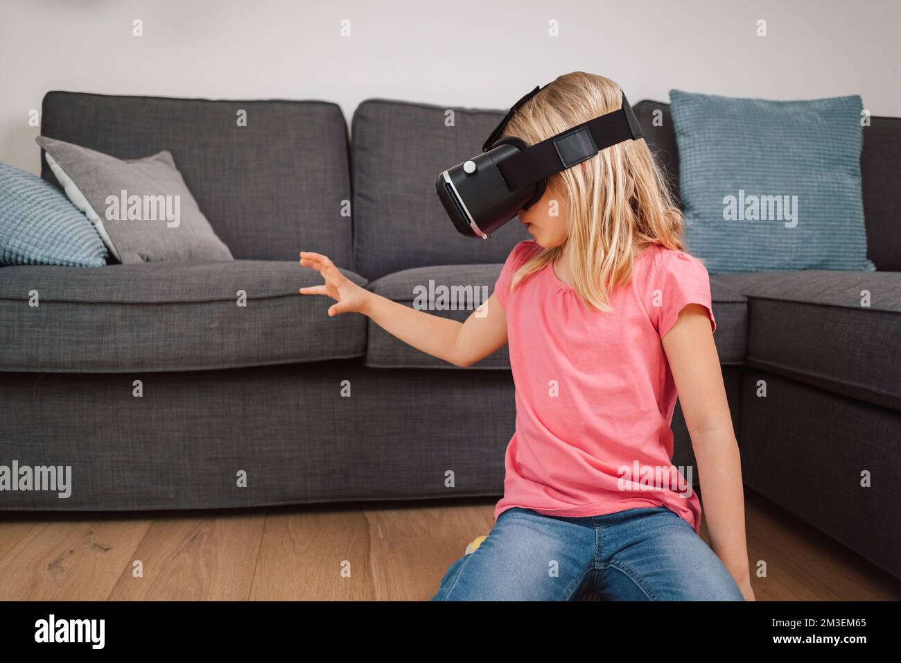 Young girl in VR headset touching air during virtual reality experience ...