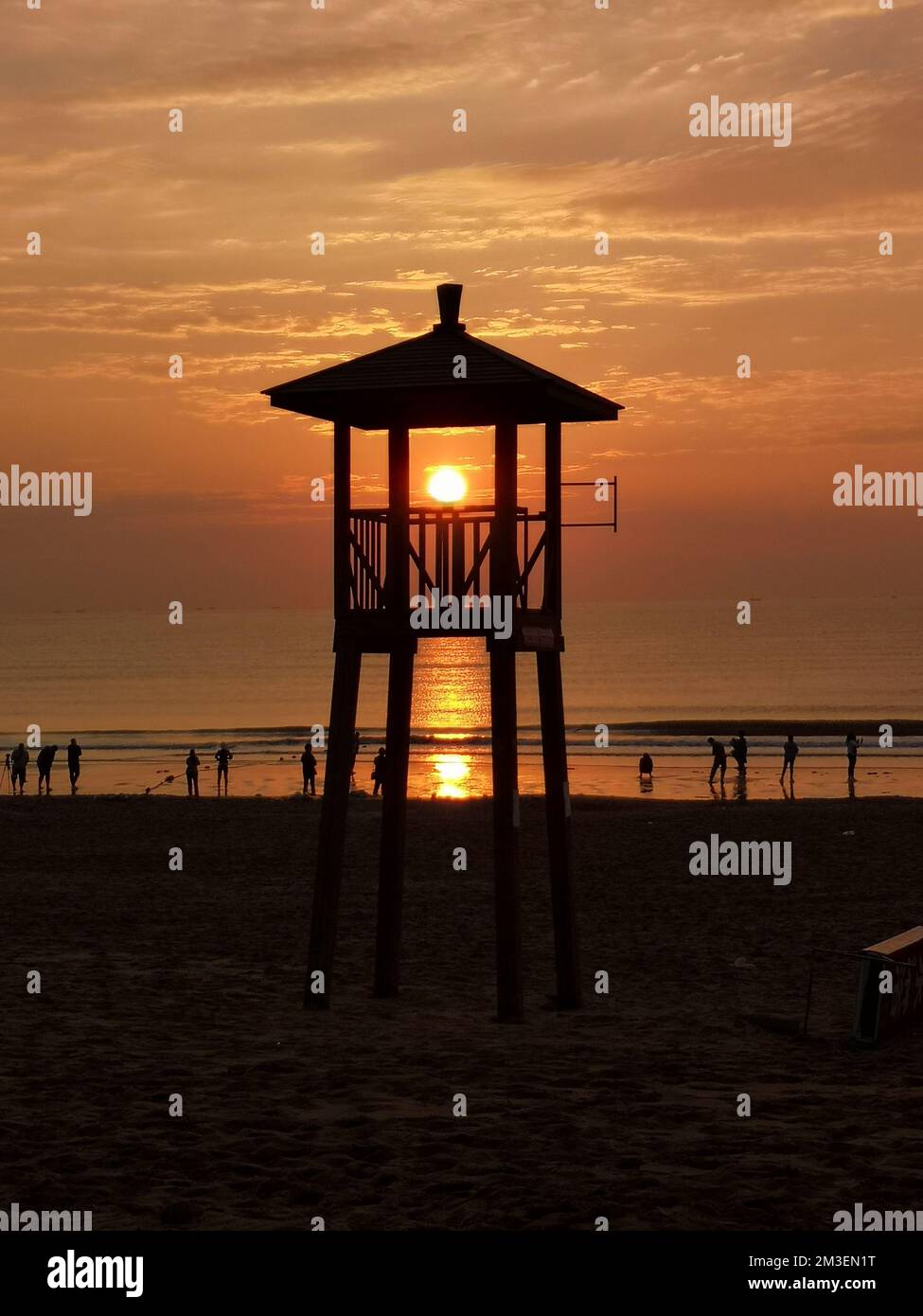 A vertical silhouette of a lifeguard shelter at sunset golden seascape ...