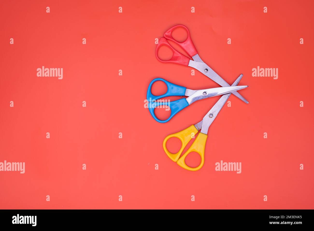 three brightly colored pairs of craft scissors isolated on an orange ...