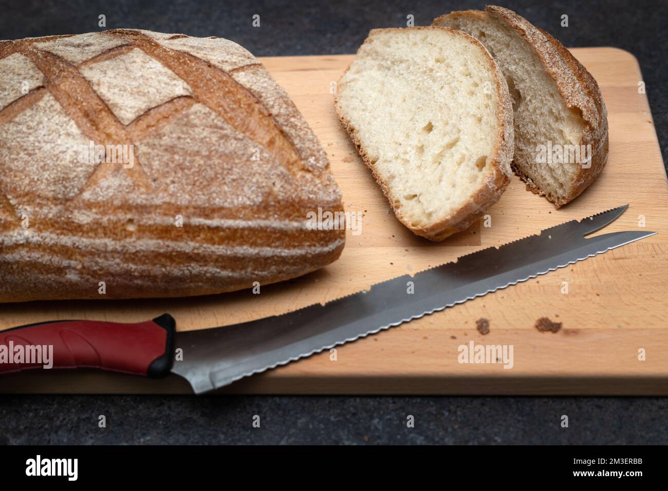 Oval loaf of freshly baked sourdough slided bread with knife on cutting ...