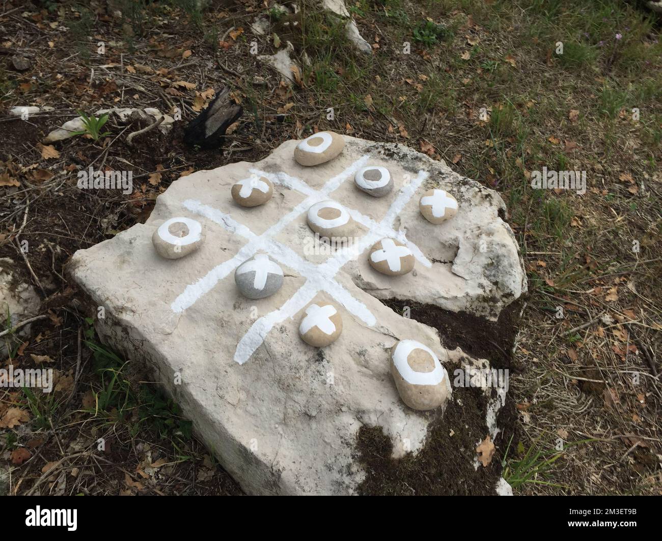 The tic-tac-toe grid and noughts and crosses marked on a rock with ...