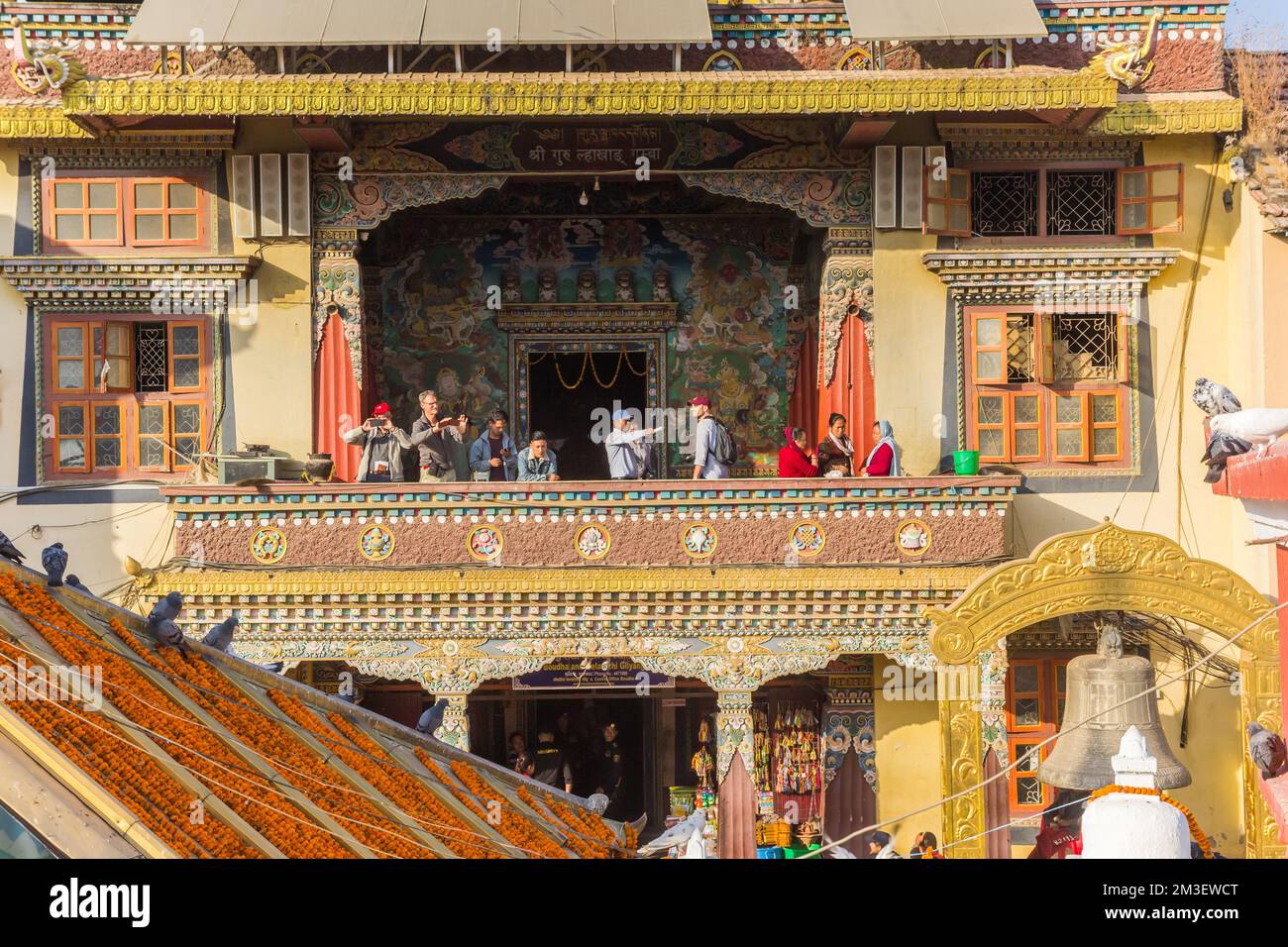 People at the balcony of a historic building at the Boudhanath stupa in ...