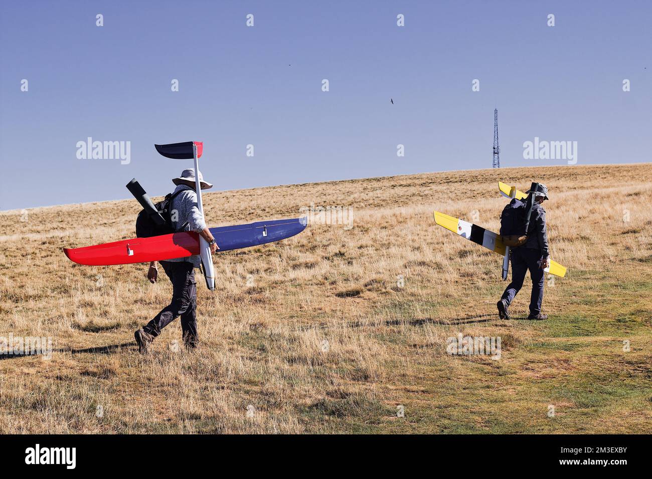 Men climb to the top of hill to launch a radio-controlled glider model ...