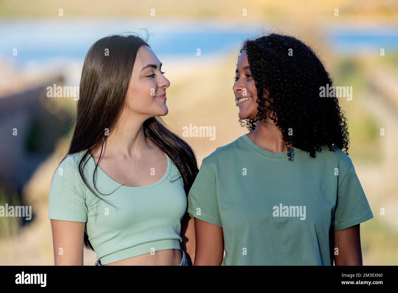 Two girls friends in the countryside walking near a river in a sunny ...