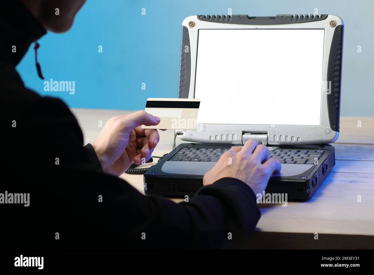 typing credit card number into computer on table and blue background ...