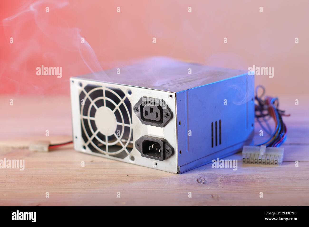 old computer power supply burning on the table and pink background ...