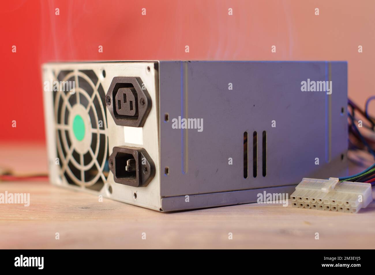 old computer power supply burning on the table and pink background ...