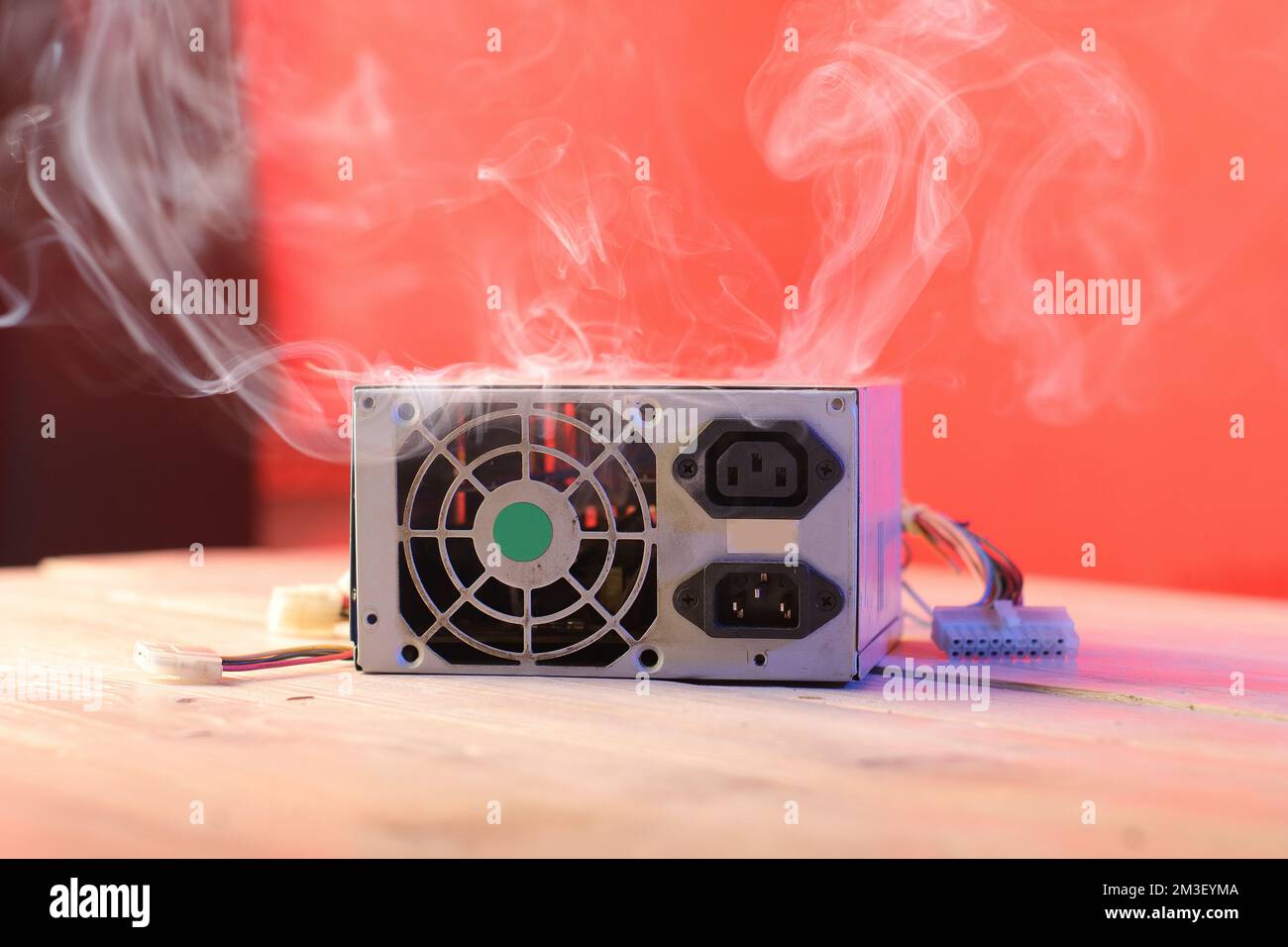 old computer power supply burning on the table and pink background ...