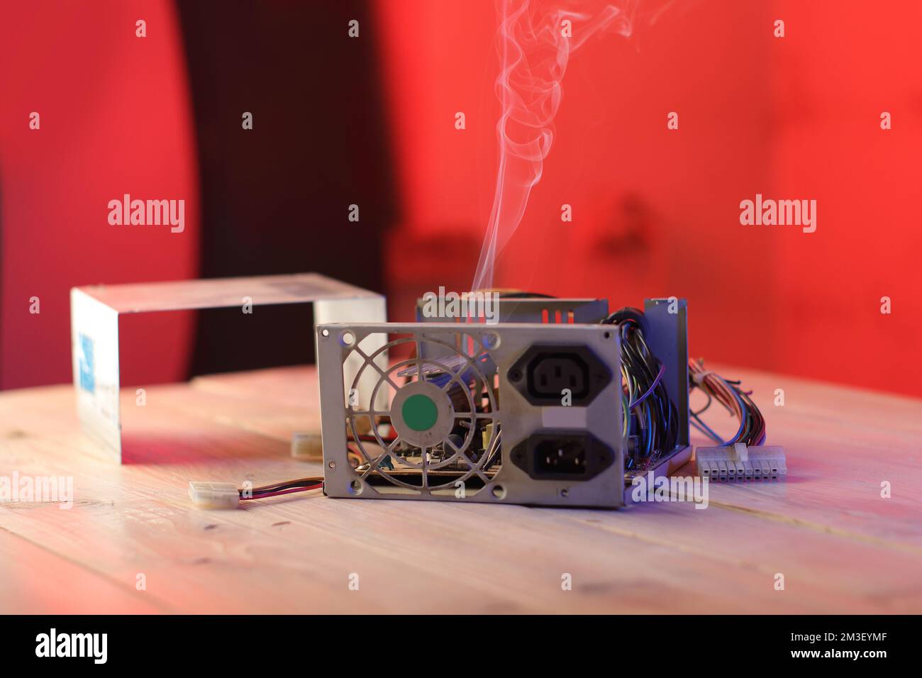 old computer power supply burning on the table and pink background ...