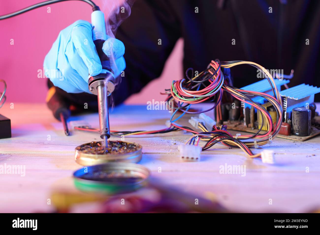 soldering iron in hand and rosin on the table and pink background Stock ...
