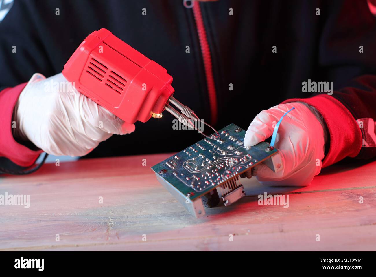 soldering on the board a red transformer soldering iron by a person on ...