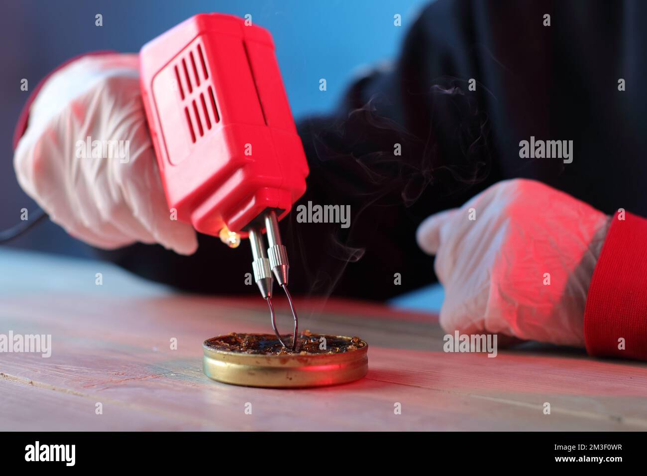 rosin melting red transformer soldering iron on table and blue ...