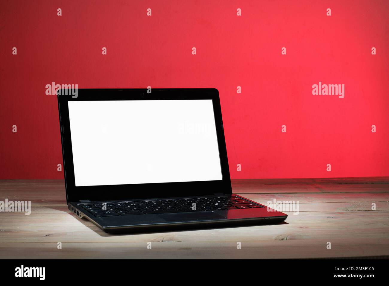 laptop with a clean white screen on the table and a red background ...