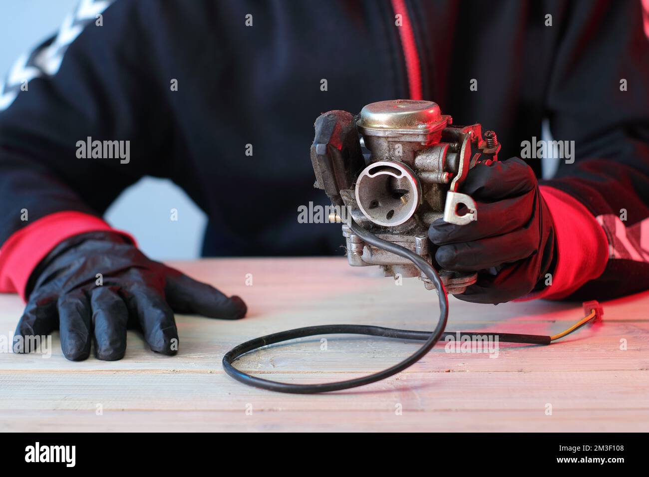 old carburetor from a four-stroke scooter on the table in the hands ...