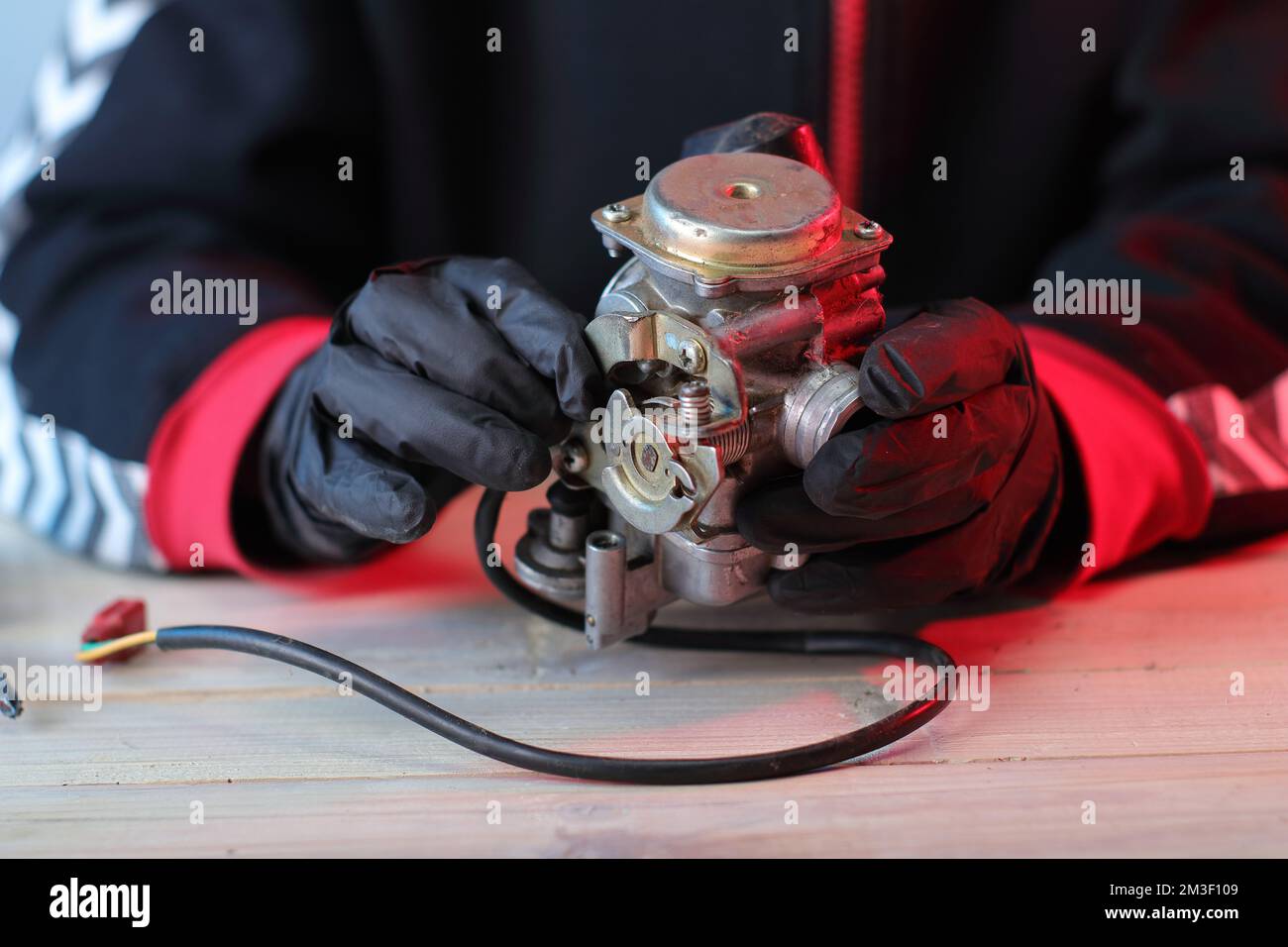old carburetor from a four-stroke scooter on the table in the hands ...