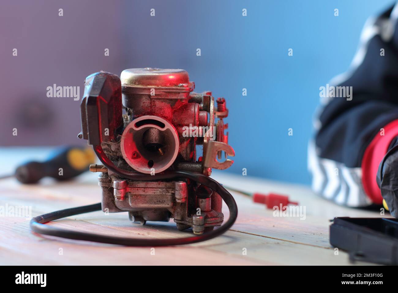 old carburetor from a four-stroke scooter on a table and blue ...
