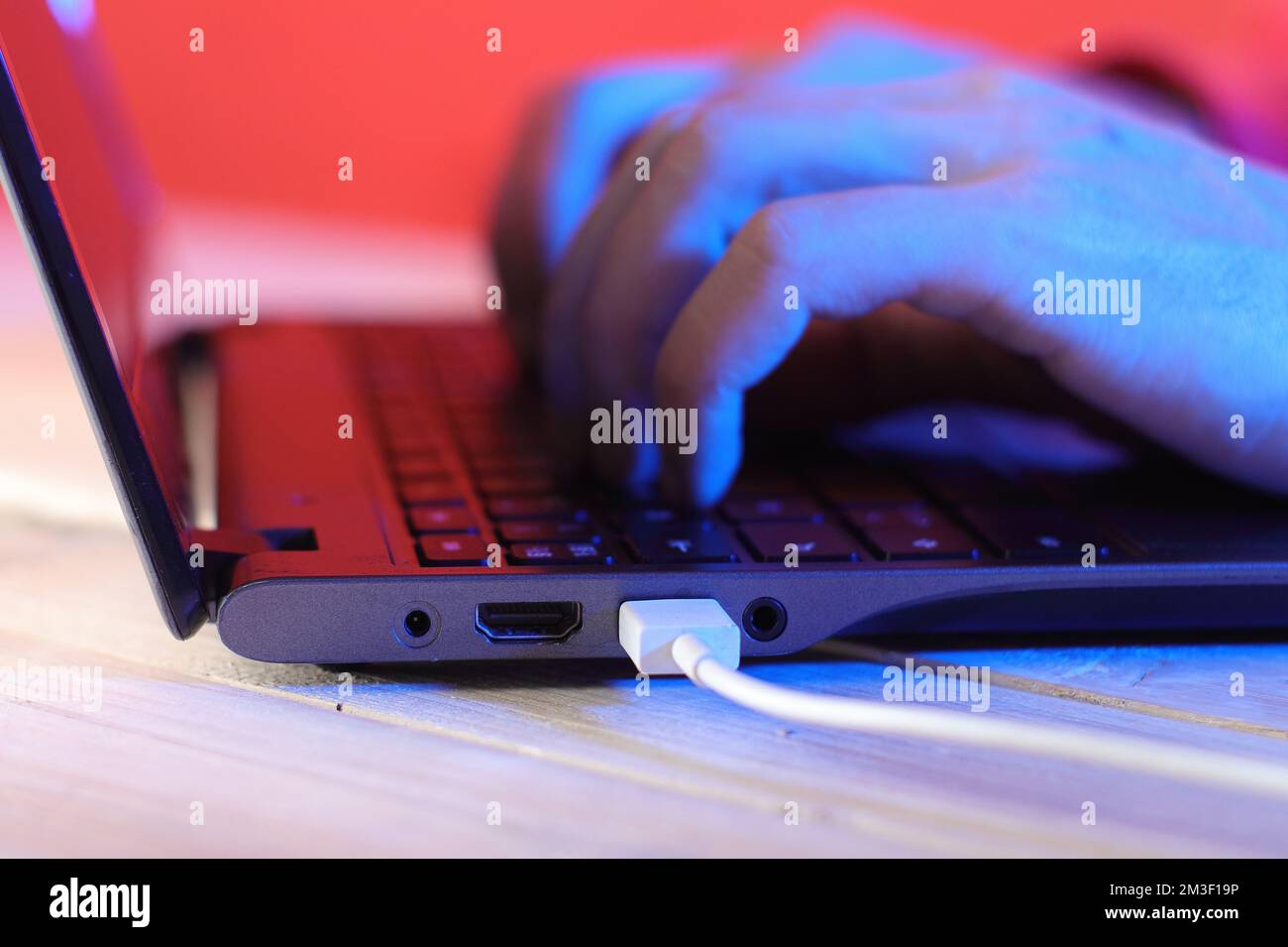 white usb cable in laptop port with hands on keyboard and colored ...