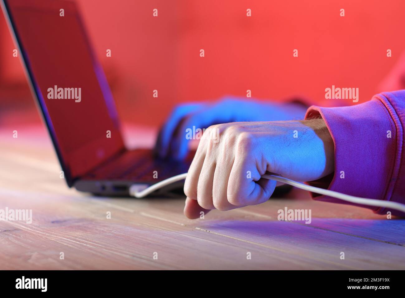 pulling usb cable from laptop port on table and colored background ...