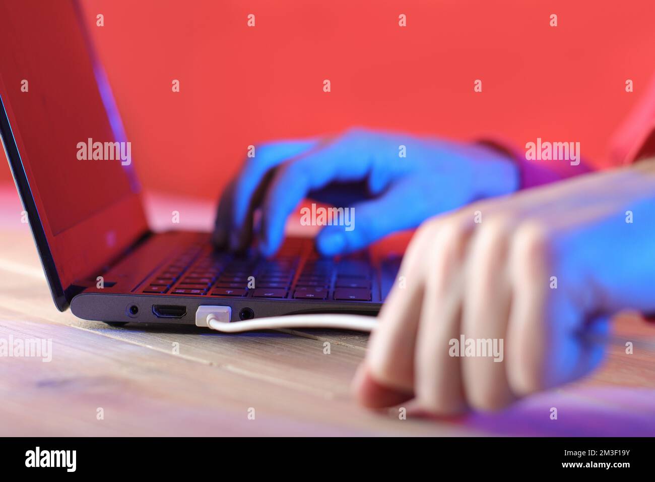 pulling usb cable from laptop port on table and colored background ...