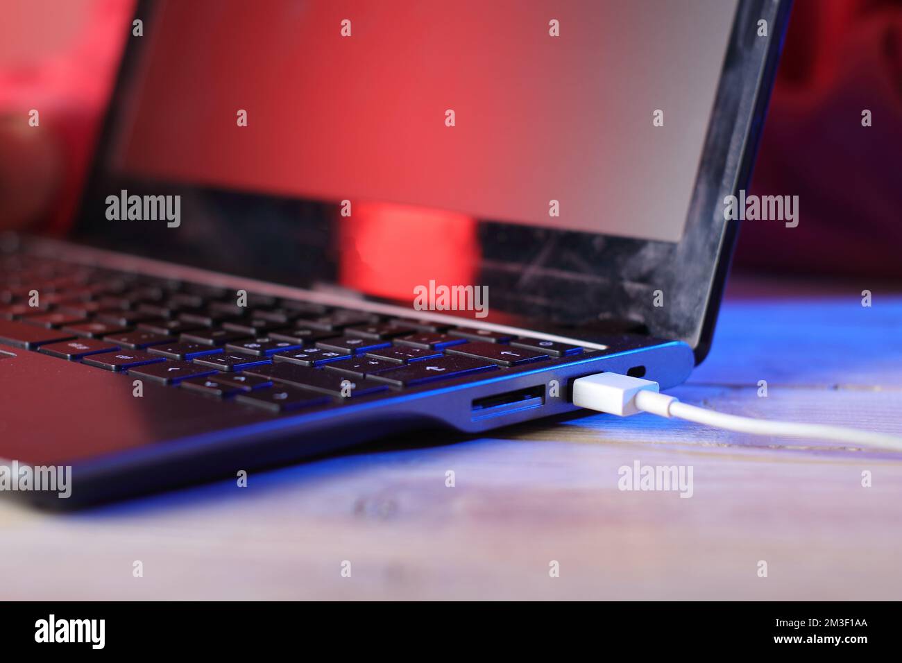 inserting usb cable into laptop on table and colored background Stock ...