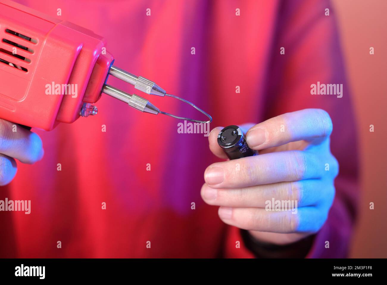 soldering a capacitor with a transformer soldering iron by a person in ...