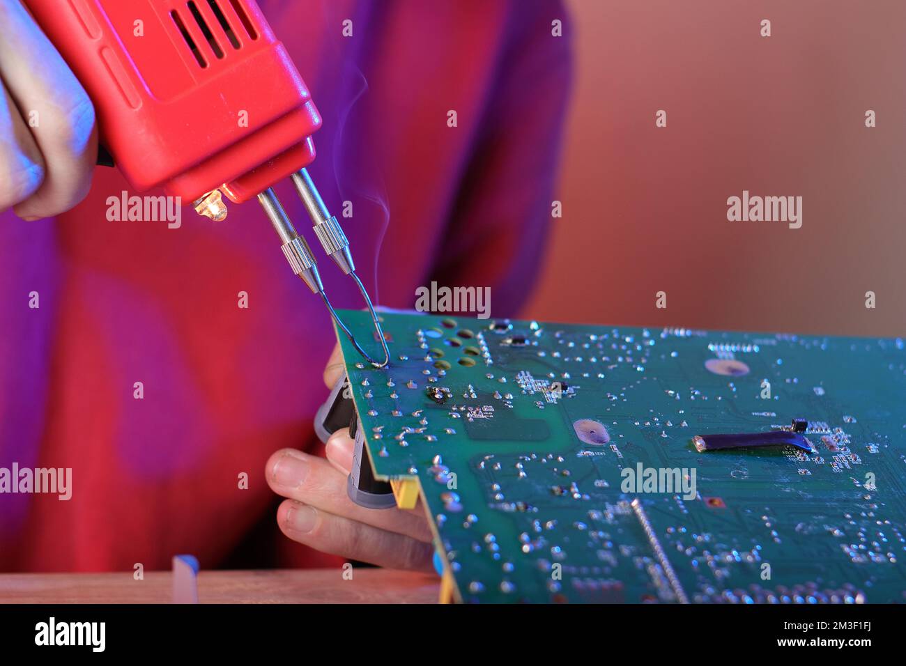 soldering the motherboard with a transformer soldering iron by a person ...