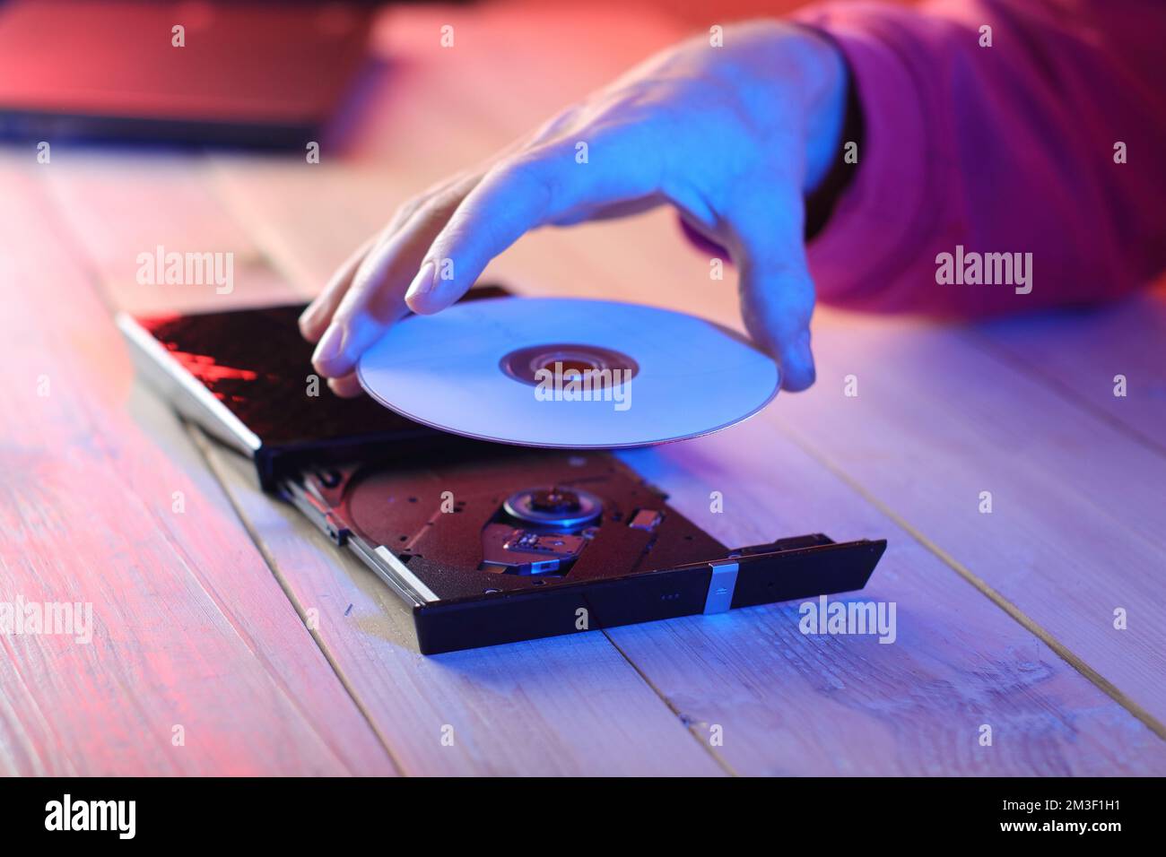 person inserting a compact disc into an optical drive into a laptop by ...