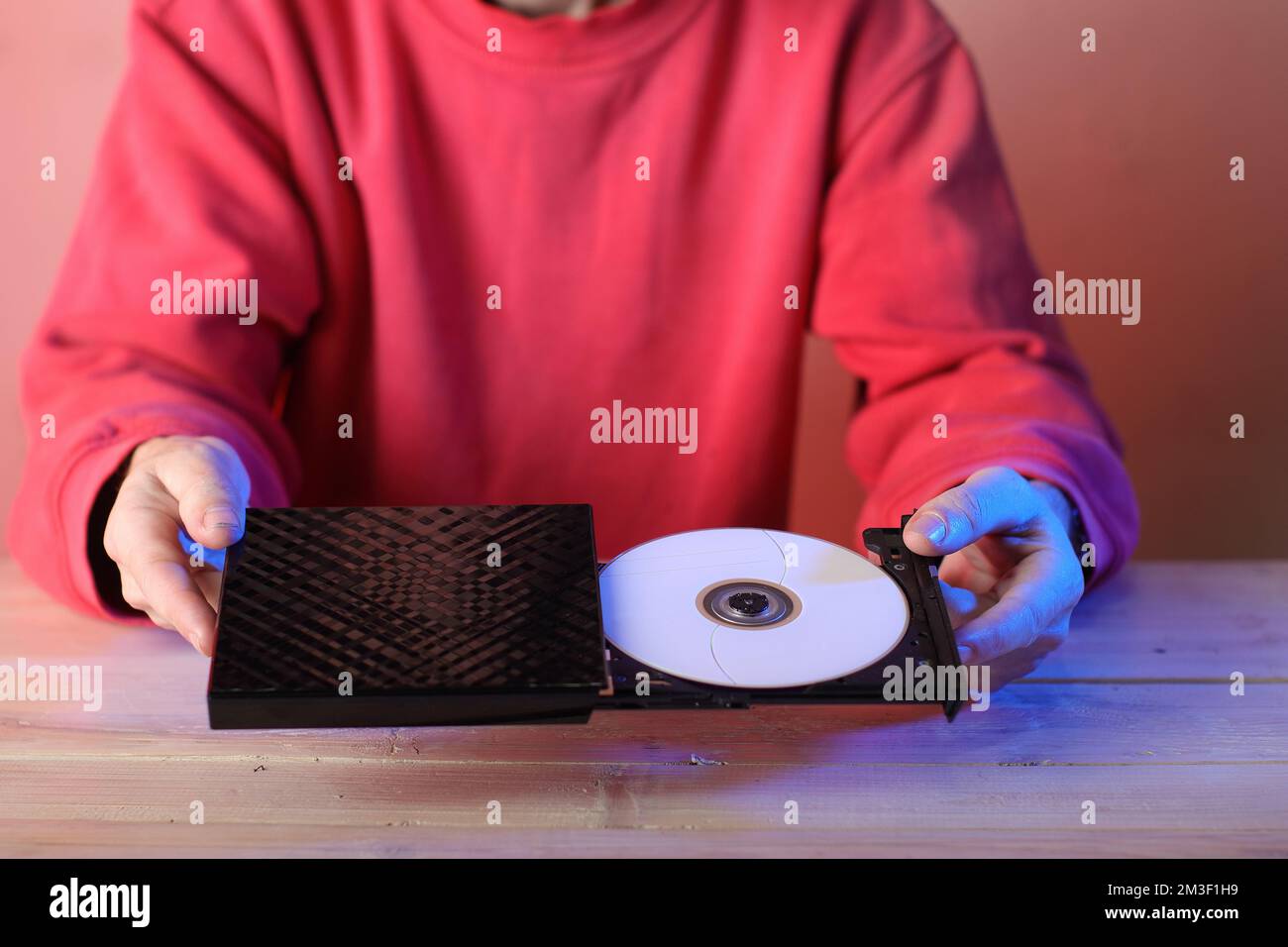 laptop optical drive with compact disc in hands on table and colored ...