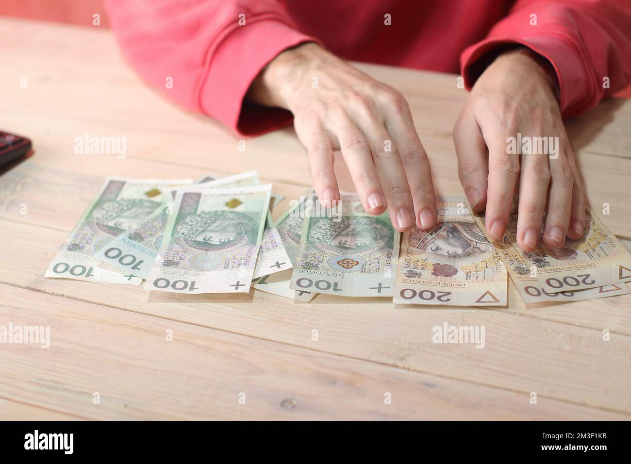 counting polish zloty banknotes with calculator on table and colored ...