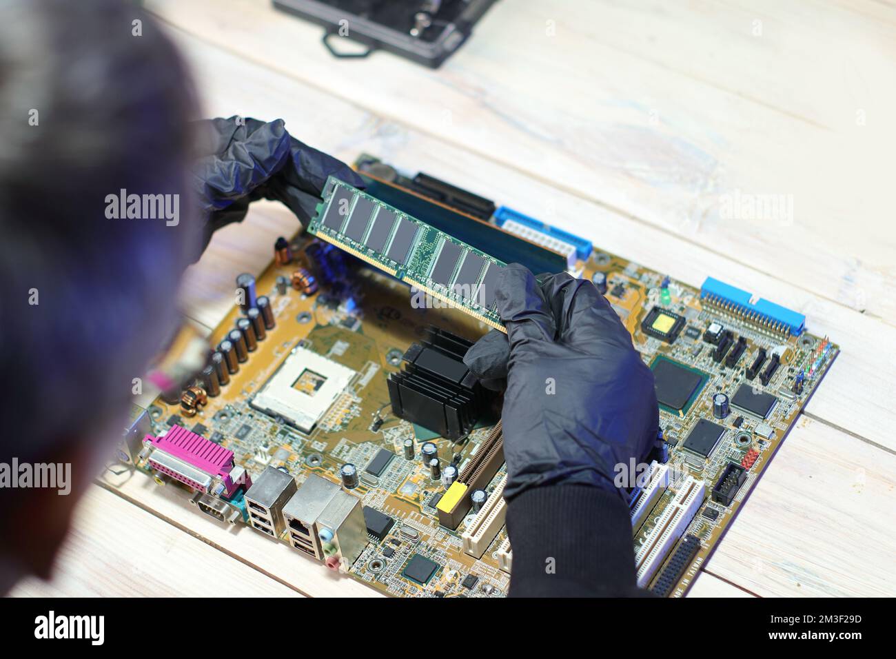 inserting ram into motherboard from computer on table and gray ...