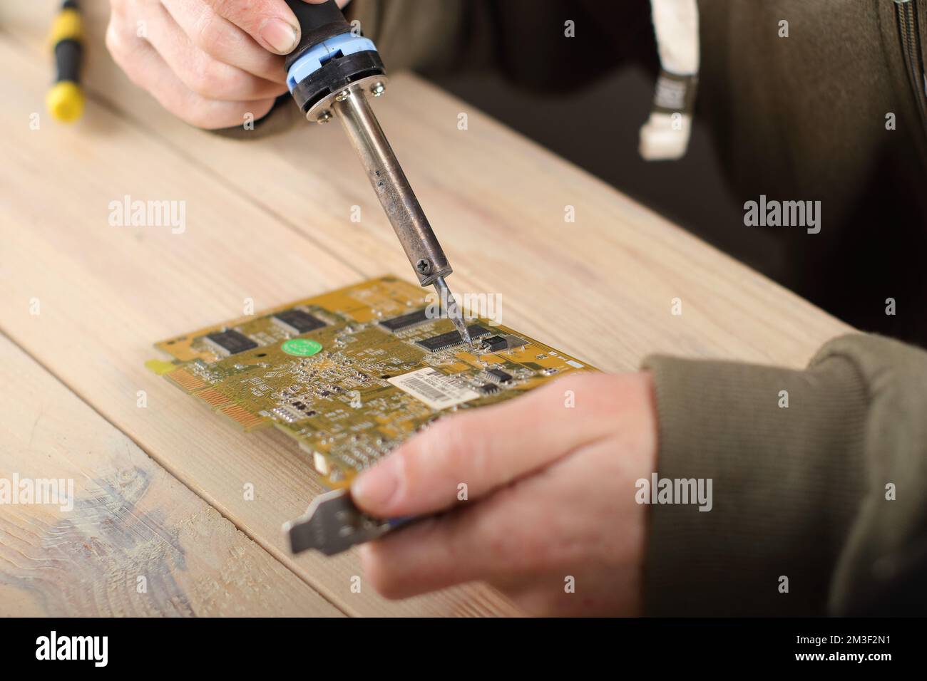 person soldering computer graphics card on table and gray background ...