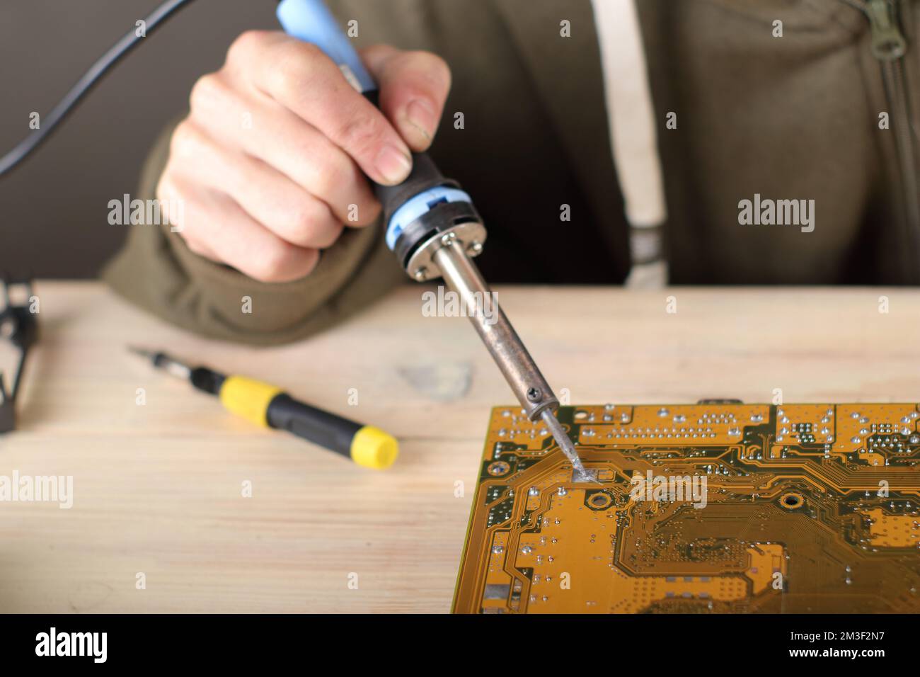 soldering computer motherboard by person on table and gray background ...