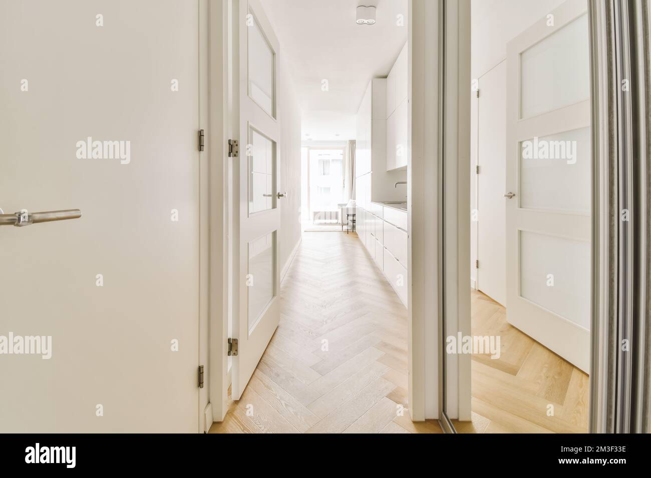 a long hallway with white walls and wood flooring on either side by ...